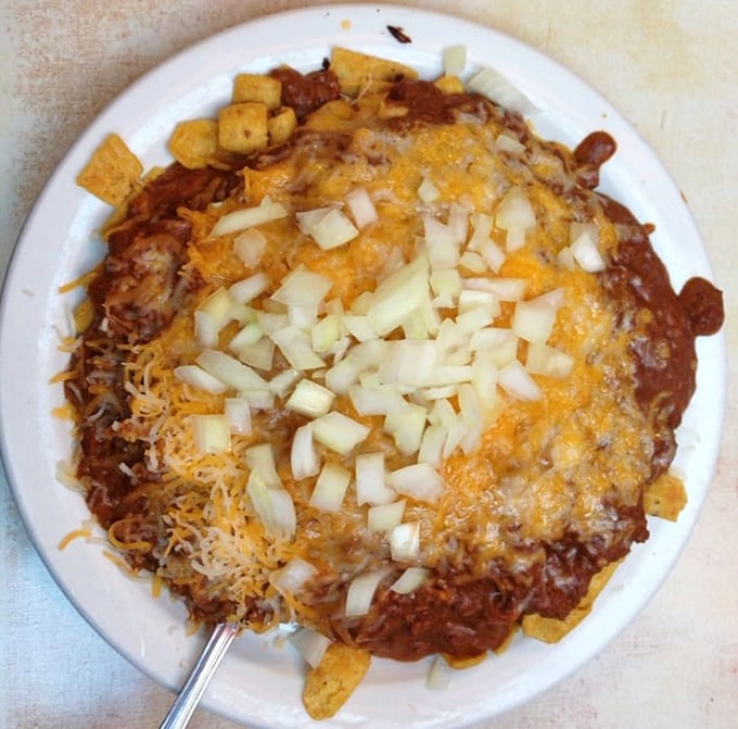 Behold the famous Frito Pie—a beautiful mess of corn chips, signature chili, melted cheese, and diced onions. Architecture that collapses deliciously with each forkful.