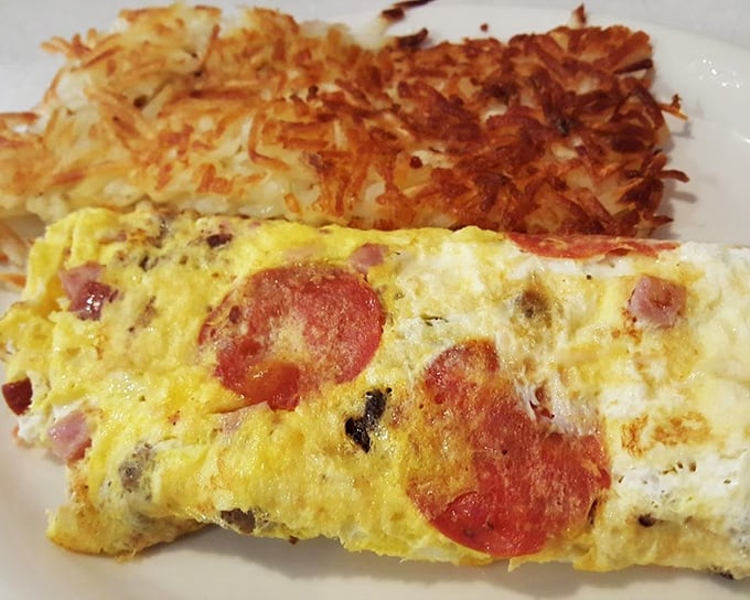 This isn't just any omelet – it's breakfast architecture at its finest. Golden-brown hash browns stand guard beside eggs studded with savory treasures.