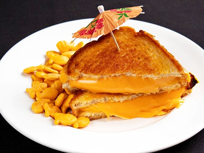 Behold the platonic ideal of a grilled cheese—golden-brown exterior, molten interior, with a tiny umbrella that says, "Yes, this is a special occasion."