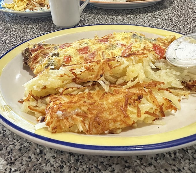 Golden, crispy hashbrowns that shatter like delicate glass with each bite, paired with a perfectly cooked omelet – this is breakfast nirvana, Wisconsin-style.
