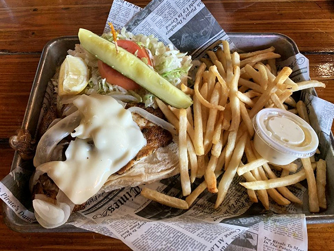 The legendary Hogfish Sandwich arrives like seafood royalty—Swiss cheese cascading over fresh-caught fish on Cuban bread with a mountain of hand-cut fries.