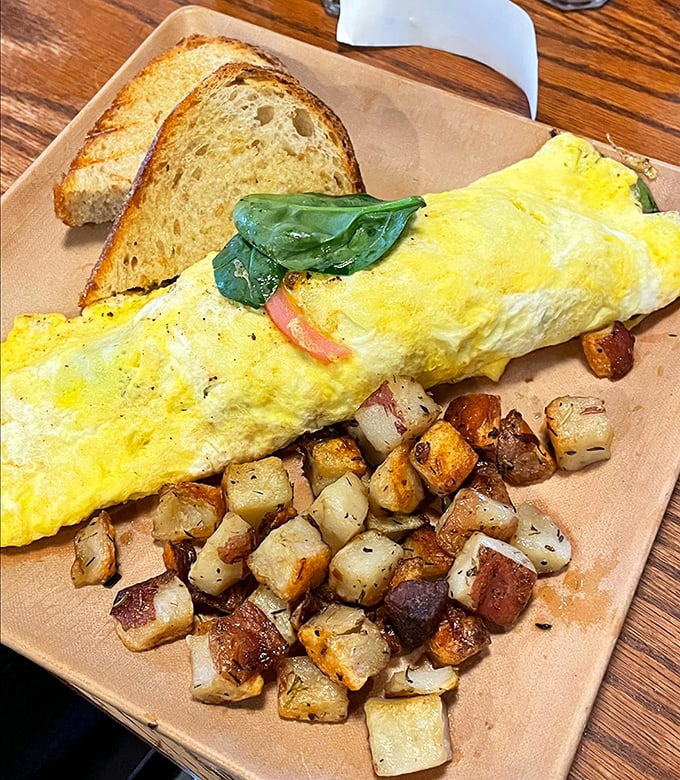 This omelet doesn't just arrive at your table—it makes an entrance, with golden perfection flanked by crispy potatoes that deserve their own fan club.