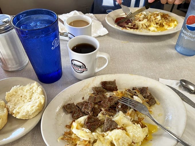 Breakfast alchemy at its finest – perfectly scrambled eggs mingling with steak, all served with a biscuit that would make your grandmother secretly jealous.