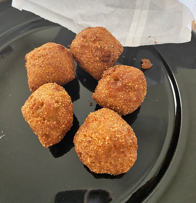 Golden-brown hush puppies with that perfect crispy exterior hiding a tender, savory interior – these little cornmeal spheres of joy are worth the trip alone.
