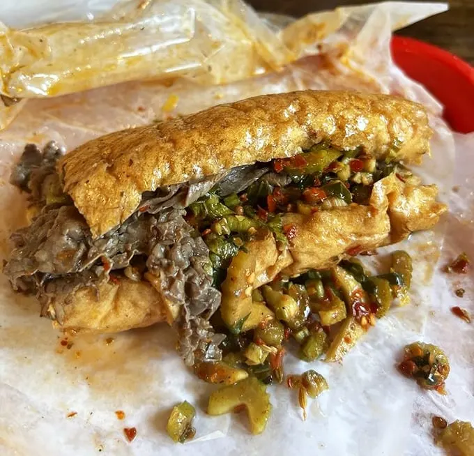 Behold the Italian beef in its natural habitat – paper-wrapped, giardiniera-topped, and gloriously messy. This isn't just a sandwich; it's Chicago's soul between bread.
