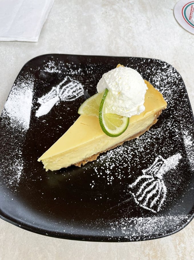 The legendary key lime pie arrives like Florida sunshine on a plate—creamy, perfectly tart filling, topped with fresh whipped cream and a lime slice garnish.
