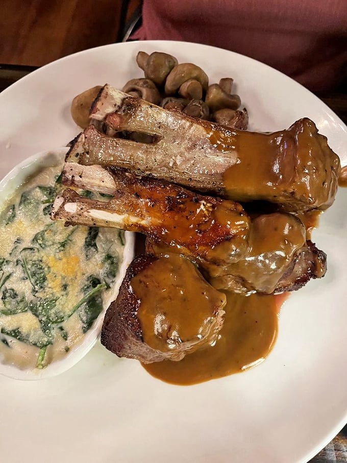 These lamb chops aren't just dinner, they're a masterpiece—perfectly frenched bones rising from a pool of savory sauce with creamed spinach playing the delicious supporting role.