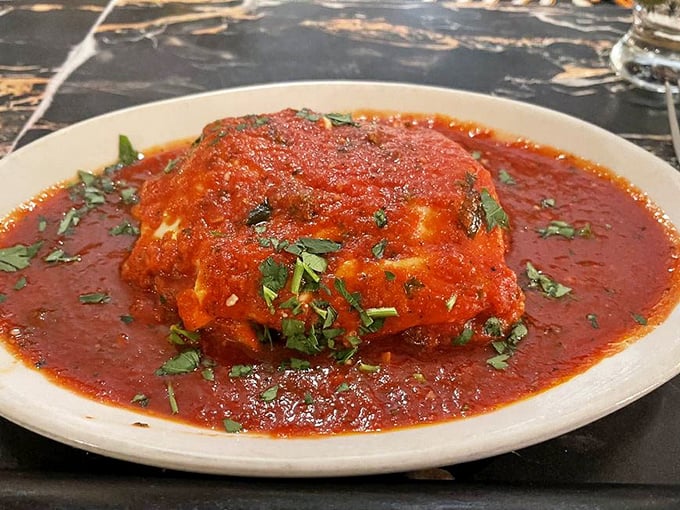 The legendary lasagna arrives like a ruby-red island in a sea of marinara – layers of pasta, cheese, and sauce that justify the cross-state pilgrimages.