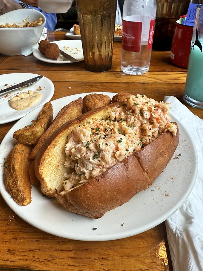 This isn't just a lobster roll—it's edible poetry. Generous chunks of sweet meat nestled in a perfectly toasted bun with golden potato wedges standing guard.