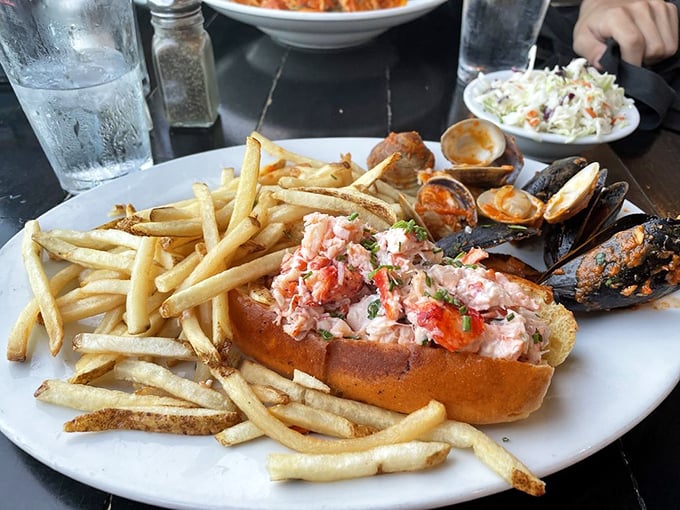 The lobster roll arrives like a celebrity making a grand entrance—chunks of sweet meat nestled in a golden bun, surrounded by an entourage of crispy fries.