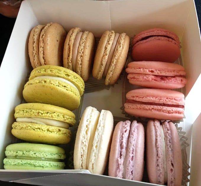 A rainbow of macarons arranged with military precision—each one a perfect circle of joy waiting to shatter delicately between your teeth.