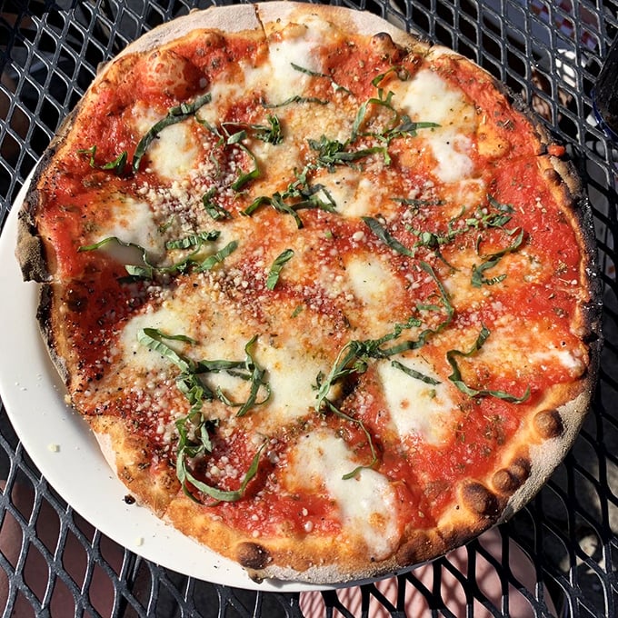 The Margherita pizza—where fresh basil dances across molten cheese and bright tomato sauce on a perfectly charred crust. Simplicity at its most sublime.