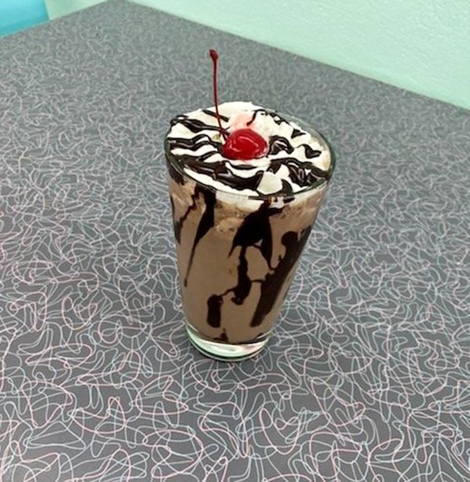 This isn't just a milkshake – it's a chocolate masterpiece topped with whipped cream, drizzled with syrup, and crowned with a cherry.