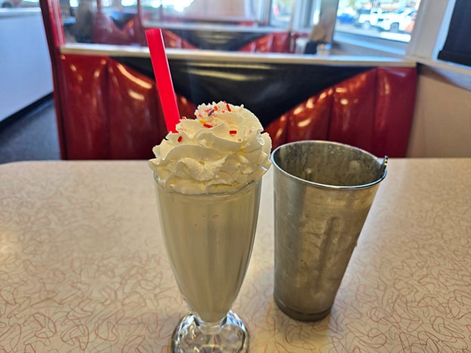 This isn't just a vanilla milkshake—it's a towering monument to dairy perfection, complete with that essential metal mixing cup on the side.