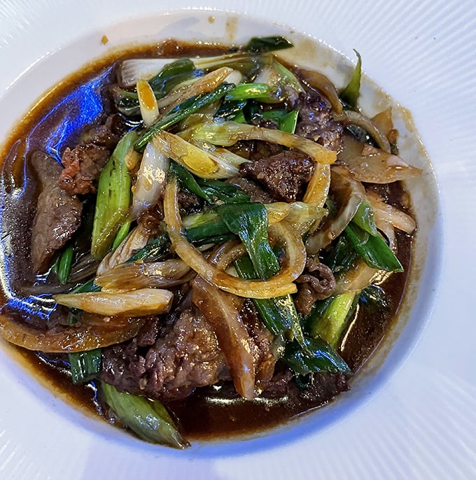 Tender slices of beef dance with green onions in a savory sauce—proof that sometimes the simplest dishes deliver the most profound flavors.