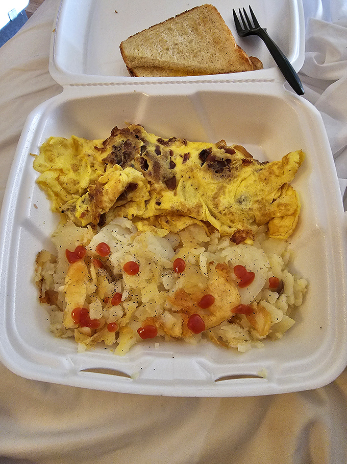 Breakfast architecture at its finest—a golden omelet that's seen more fillings than a dentist's office, paired with home fries that demand attention.
