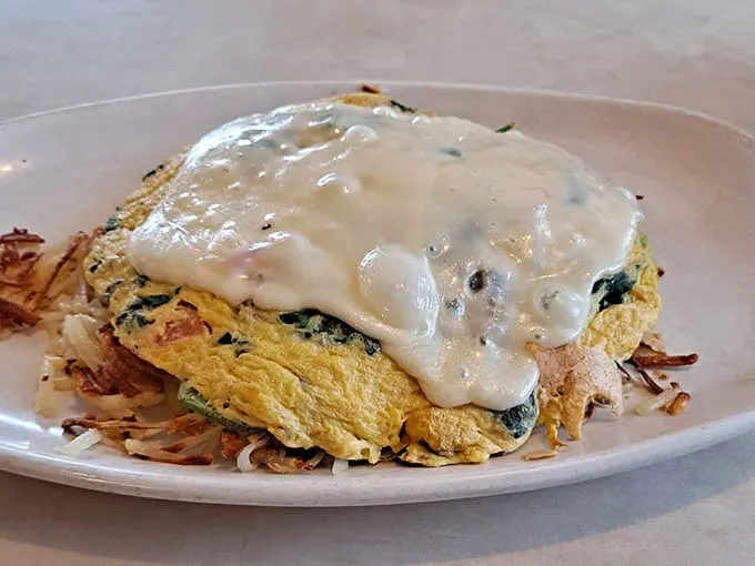 This isn't just an omelet—it's a golden pillow of egg perfection crowned with a sauce that would make French chefs nod in approval.