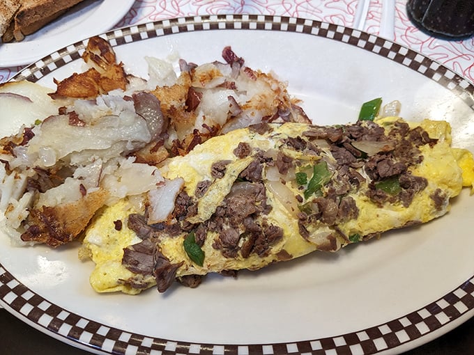 This isn't just an omelet—it's a masterpiece of morning architecture with perfectly folded eggs embracing savory steak and crispy hash browns.