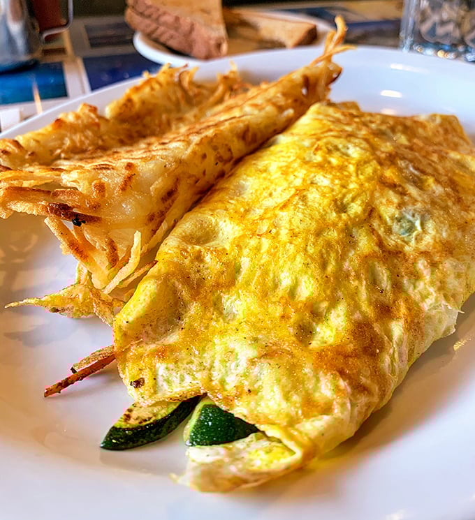 This isn't just any omelet—it's a masterclass in egg architecture, with crispy edges giving way to a pillowy interior that cradles fresh vegetables. 