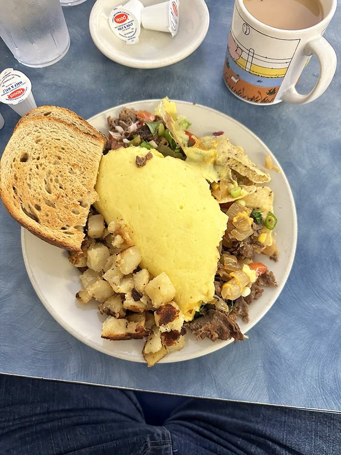 Breakfast architecture at its finest. This omelet doesn't just sit on the plate—it commands it, with home fries standing guard like delicious sentinels.