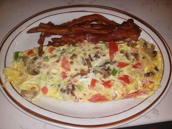 Behold the Western omelet in its natural habitat – fluffy egg exterior giving way to a treasure trove of peppers, ham, and cheese.