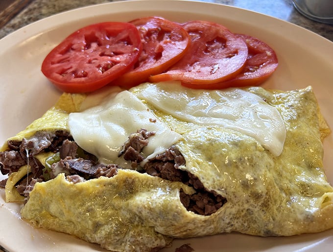 This isn't just an omelet—it's a masterclass in egg architecture, with perfectly melted cheese cascading over seasoned steak.