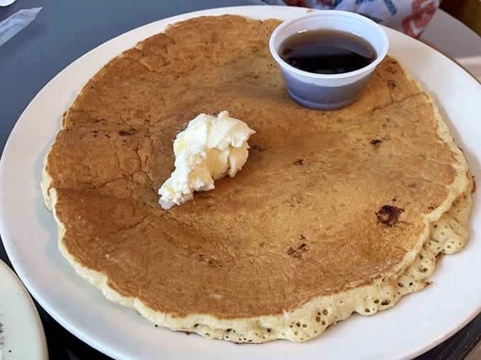 This pancake isn't just big—it's the size of a frisbee with the structural integrity of a cloud. Butter melting like a summer romance.