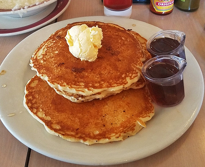 Golden pancakes that could make IHOP executives weep with envy. That pat of butter melting on top isn't just garnish – it's performance art.