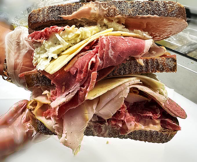 Architecture of deliciousness! This towering creation showcases the art of proper sandwich construction – meat, cheese, and slaw in perfect harmony.
