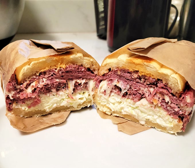 Behold the pastrami masterpiece – layers upon layers of pink perfection that would make a cardiologist weep with conflicted emotions.