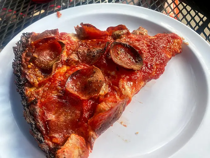 That blackened crust isn't a mistake – it's pizza nirvana. The pepperoni cups cradle tiny pools of flavor that'll haunt your dreams.