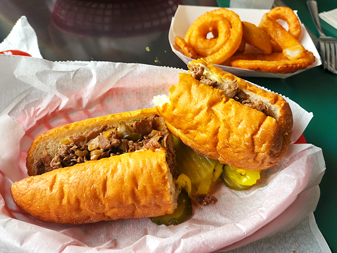 The legendary Philly cheese steak in all its glory—tender meat, melted cheese, and those perfectly golden onion rings on the side. Napkins: non-negotiable.