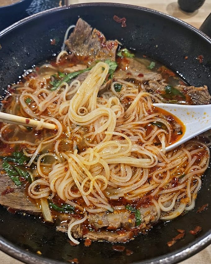 This steaming bowl of noodle soup isn't just comfort food—it's a hug in liquid form, with tender beef and herbs dancing in perfect harmony.