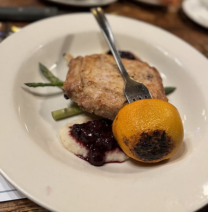 This isn't just a pork chop – it's a masterclass in simplicity, perfectly seared and served with asparagus and a charred orange that adds just the right citrus punch.