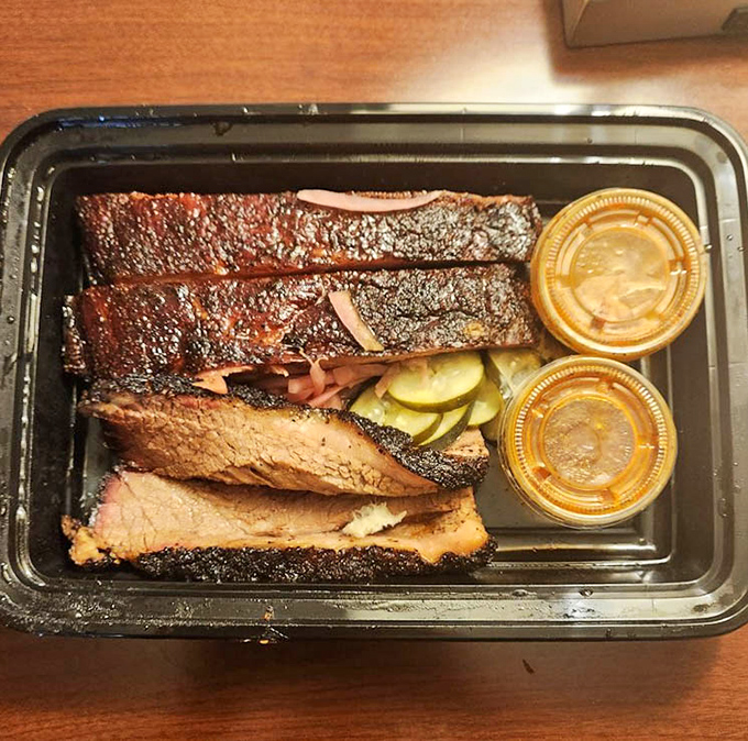 Brisket with that textbook smoke ring and bark that would make a Texan weep with joy. Those pickle chips aren't just garnish—they're essential acid balance.