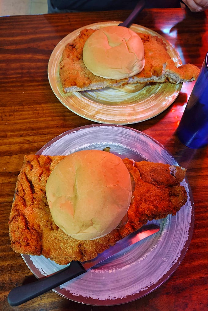 The infamous pork tenderloin in all its glory—a masterpiece of meat that makes the bun look like it's playing a supporting role in a blockbuster film.