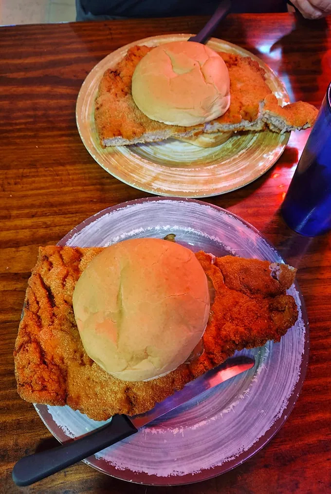 The infamous pork tenderloin in all its glory—a masterpiece of meat that makes the bun look like it's playing a supporting role in a blockbuster film.