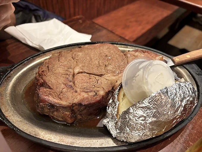 Prime rib so tender it practically surrenders to your fork. That foil-wrapped baked potato standing by like a loyal sidekick ready for buttery action.
