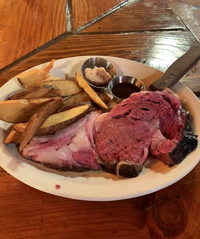 This prime rib arrives like a carnivore's dream—perfectly pink, accompanied by golden steak fries and those essential sides of jus and horseradish.
