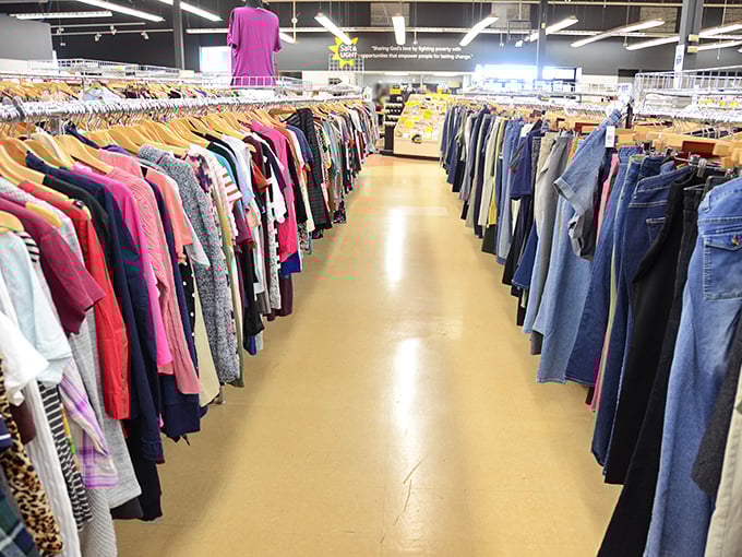 Organized chaos never looked so good—clothing aisles create a rainbow road of possibilities where your next favorite outfit patiently waits.