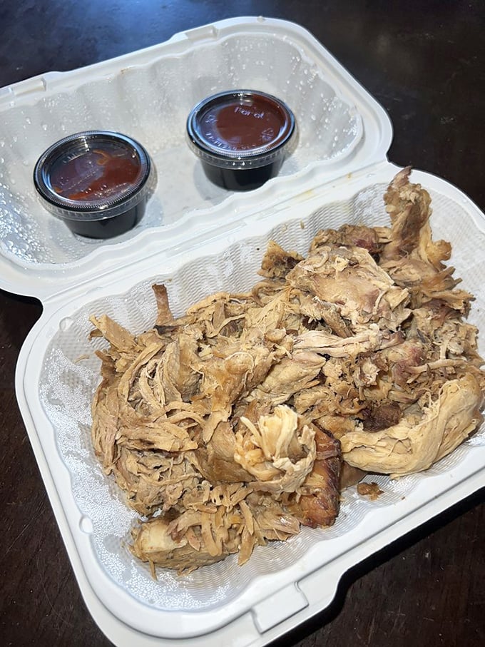 Pulled pork so tender it practically surrenders to your fork. Those two sauce cups aren't just condiments—they're flavor companions for the journey.