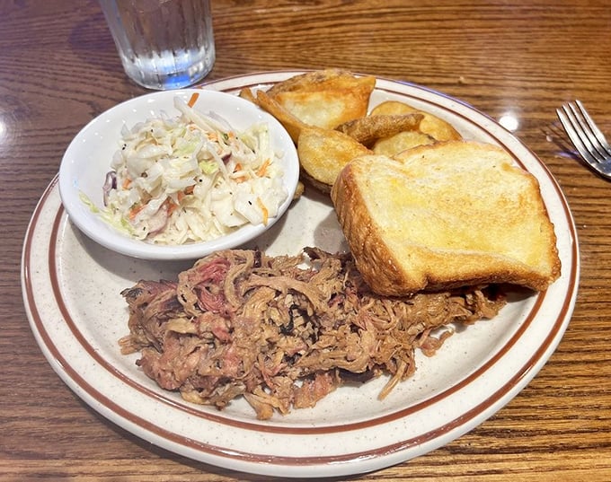 Tender strands of pulled pork alongside creamy coleslaw and Texas toast—a holy trinity of Southern comfort that speaks directly to your soul.