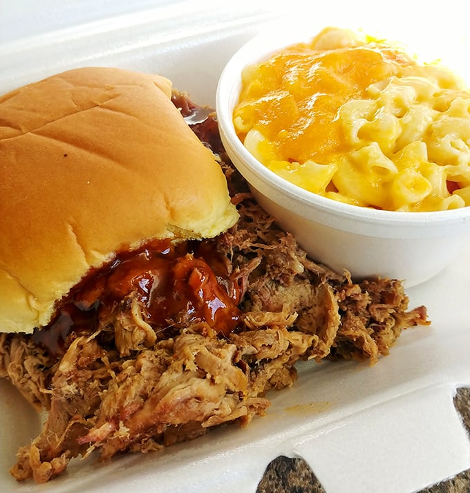 This pulled pork sandwich isn't just food; it's edible poetry. Tender strands of smoky pork spilling over a humble bun with mac and cheese standing guard.