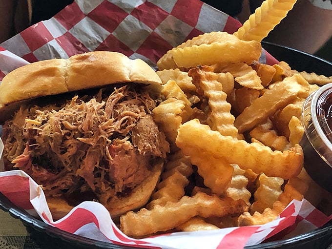 Behold the star of our show: pulled pork piled high on a sturdy bun with crispy fries standing guard. Napkins required, regrets impossible.