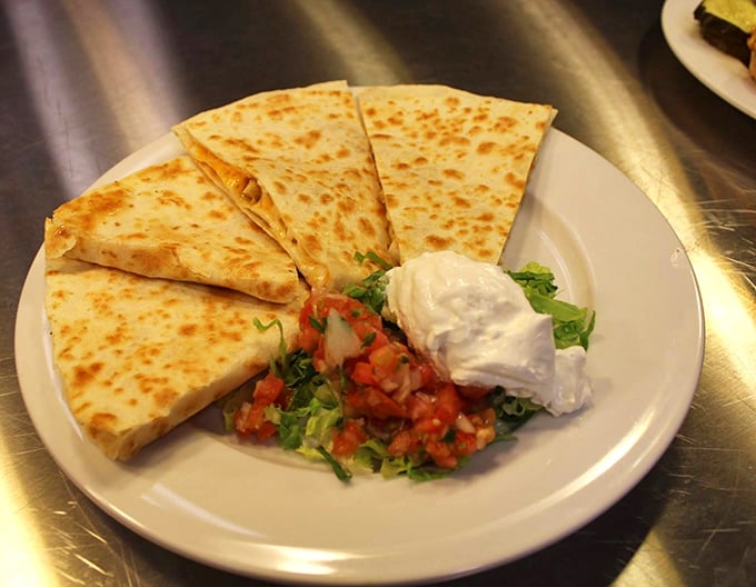 Golden-brown quesadilla triangles arranged like sun rays, accompanied by fresh pico de gallo and a cloud of sour cream – simplicity elevated to art form.