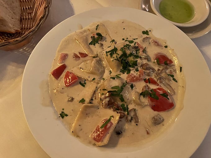 Pillows of pasta perfection! These ravioli swim in a creamy sauce dotted with fresh tomatoes and mushrooms – comfort food that hits all the high notes.