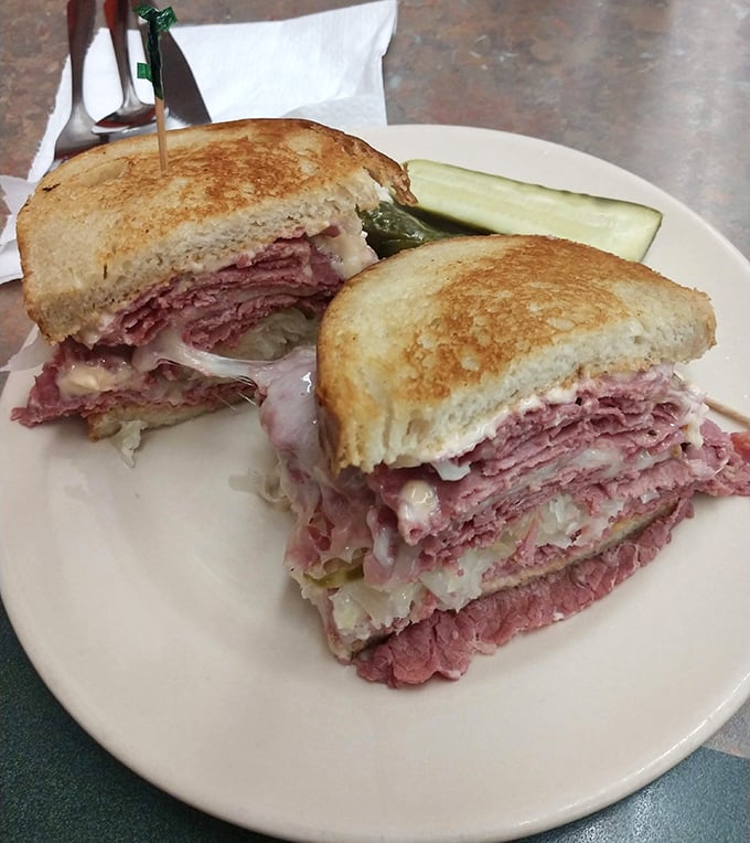 Behold the Reuben in its natural habitat—perfectly grilled rye, a mountain of corned beef, and sauerkraut applied by someone who understands proportion. That pickle isn't just a garnish, it's a necessity.