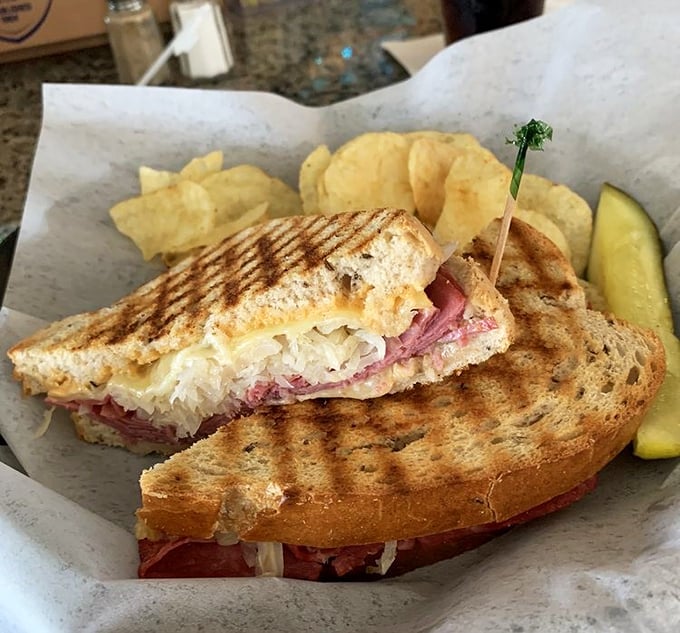 Behold the legendary Reuben in its natural habitat—perfectly grilled rye, sauerkraut peeking out, and a pickle standing guard. This is sandwich royalty.