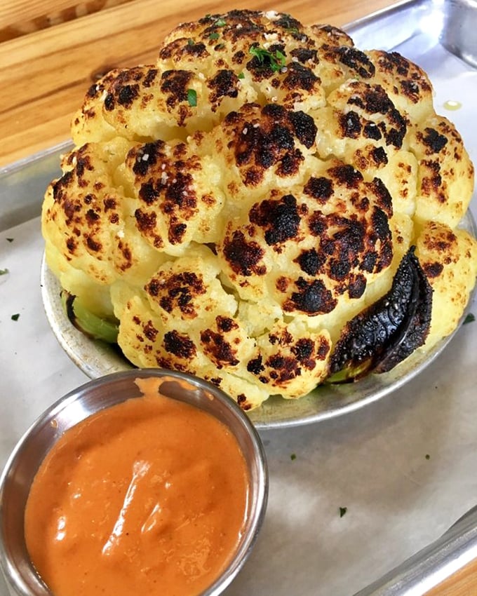 Behold the cauliflower that launched a thousand return visits—charred to perfection and served with a sauce that makes vegetables feel like an indulgence, not a obligation.