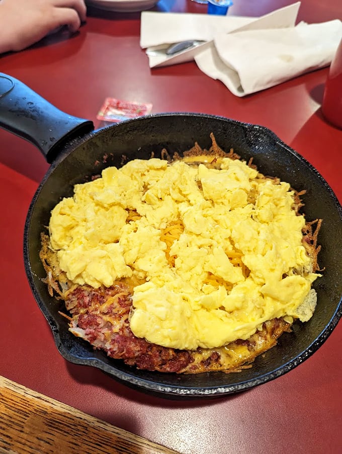 Behold the star attraction – scrambled eggs nestled atop a bed of hash browns in a cast-iron skillet. Breakfast perfection achieved!